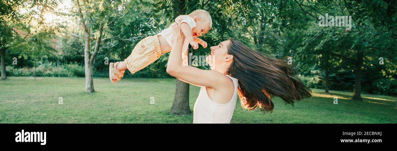 Young mother spinning toddler baby boy outdoor. Parent playing with ...