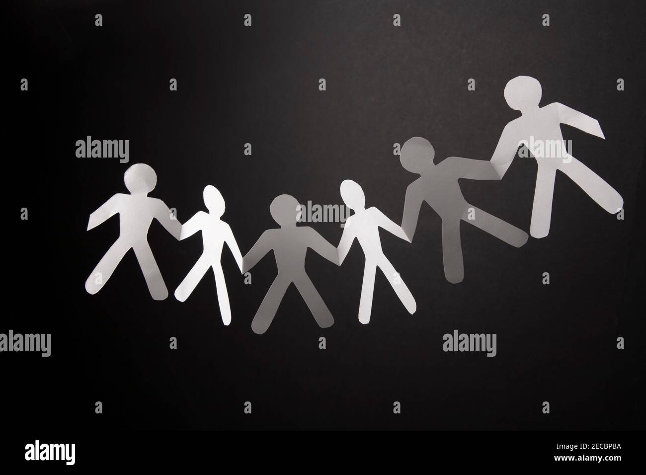 A string of horizontal white paper dolls on a black background Stock ...