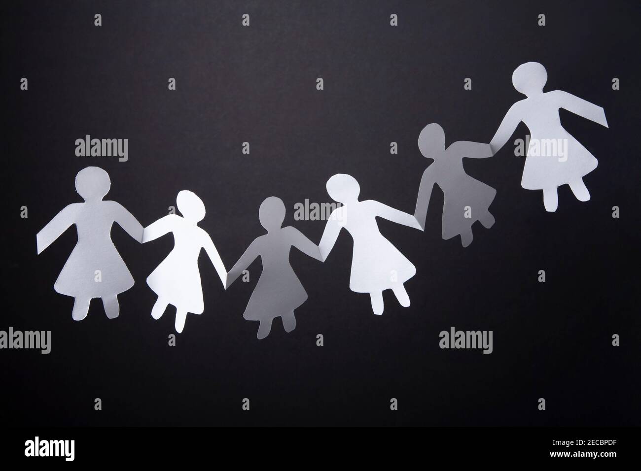 A string of horizontal white paper dolls on a black background Stock ...