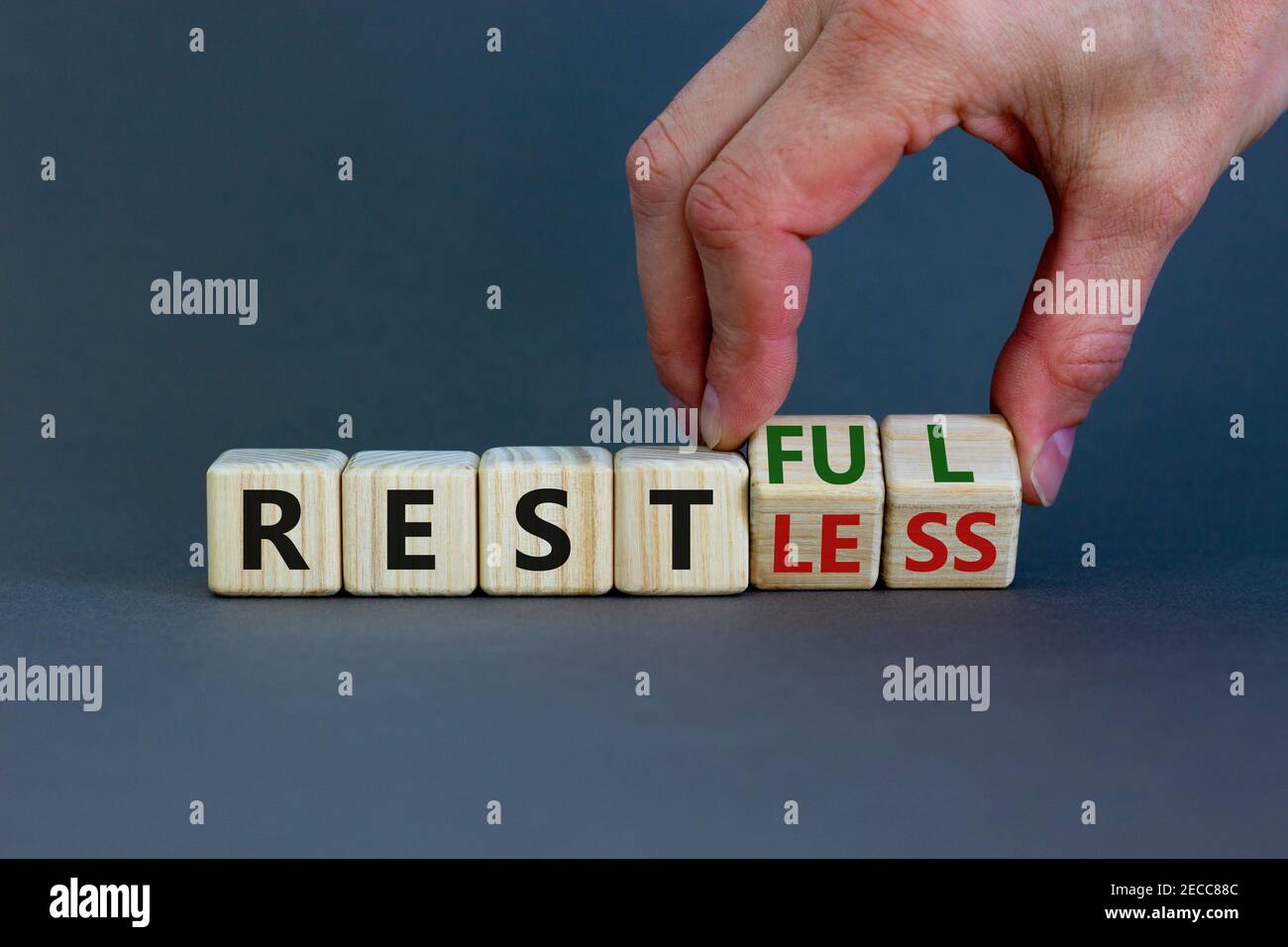 Restless or restful symbol. Businessman turns wooden cubes, changes the word 'restless' to ...