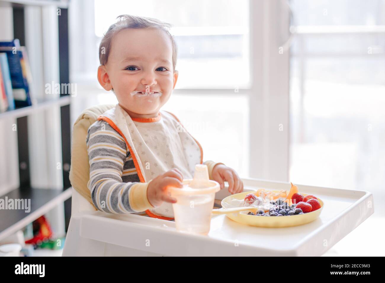 Cute Caucasian baby boy eating ripe berries and fruits with yogurt ...