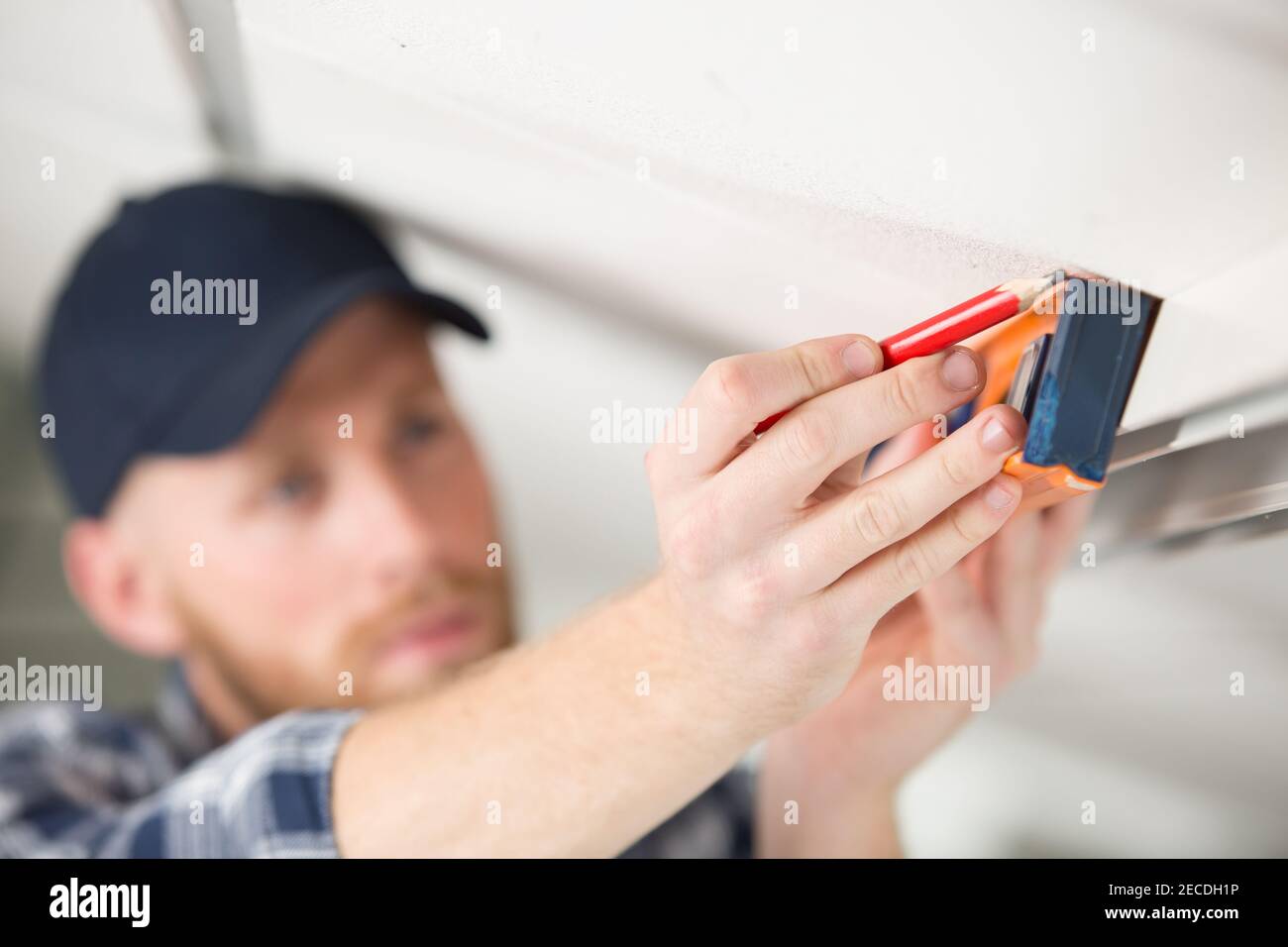 man measuring metal bar in roof space Stock Photo - Alamy