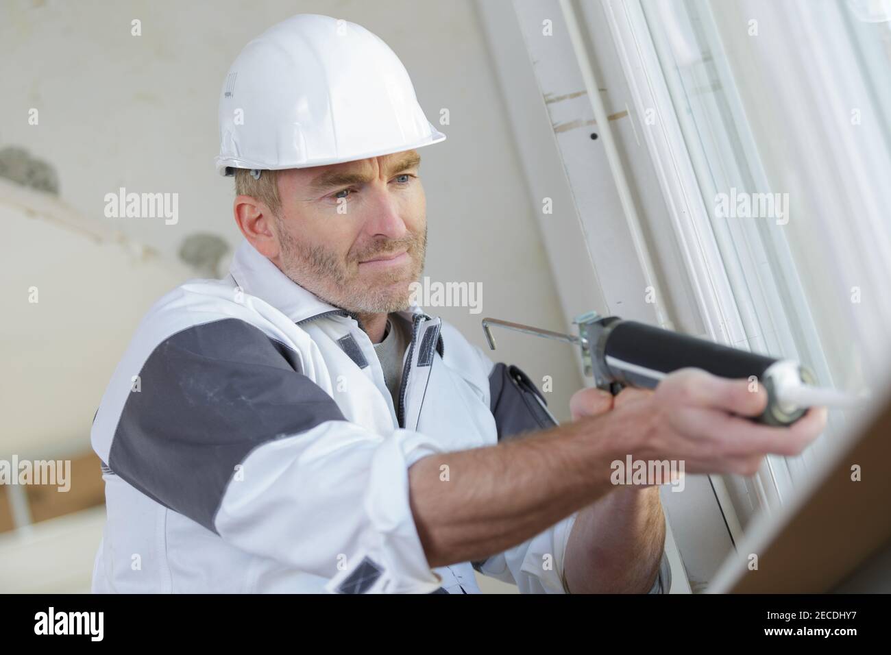 builder installing silicone in a window seal Stock Photo - Alamy