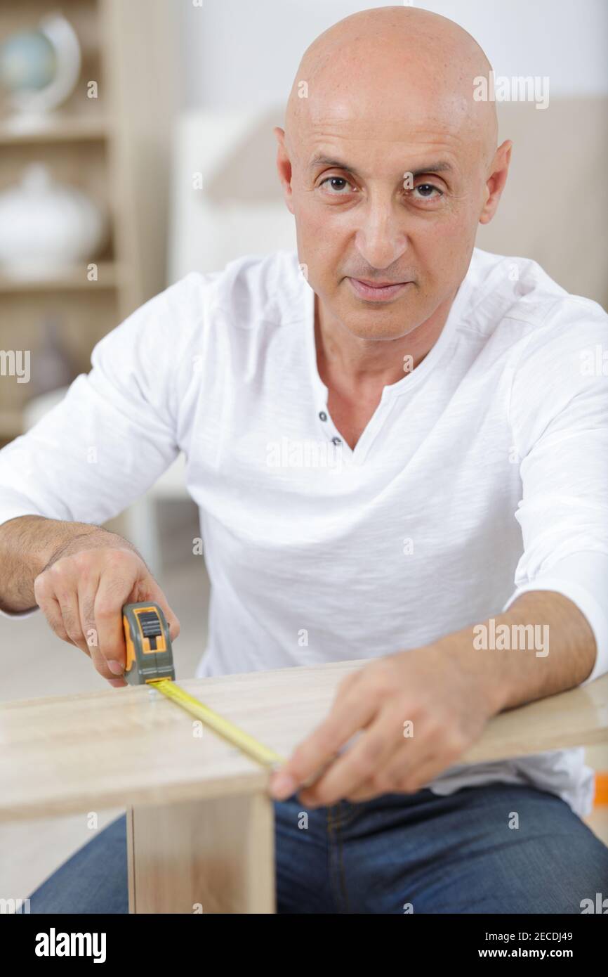 man measuring wood piece for furniture assembling Stock Photo - Alamy