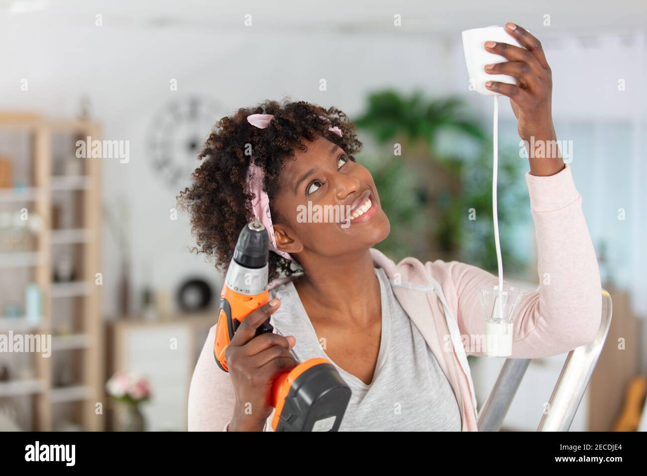 woman installing light in the home using cordless power-tool Stock ...
