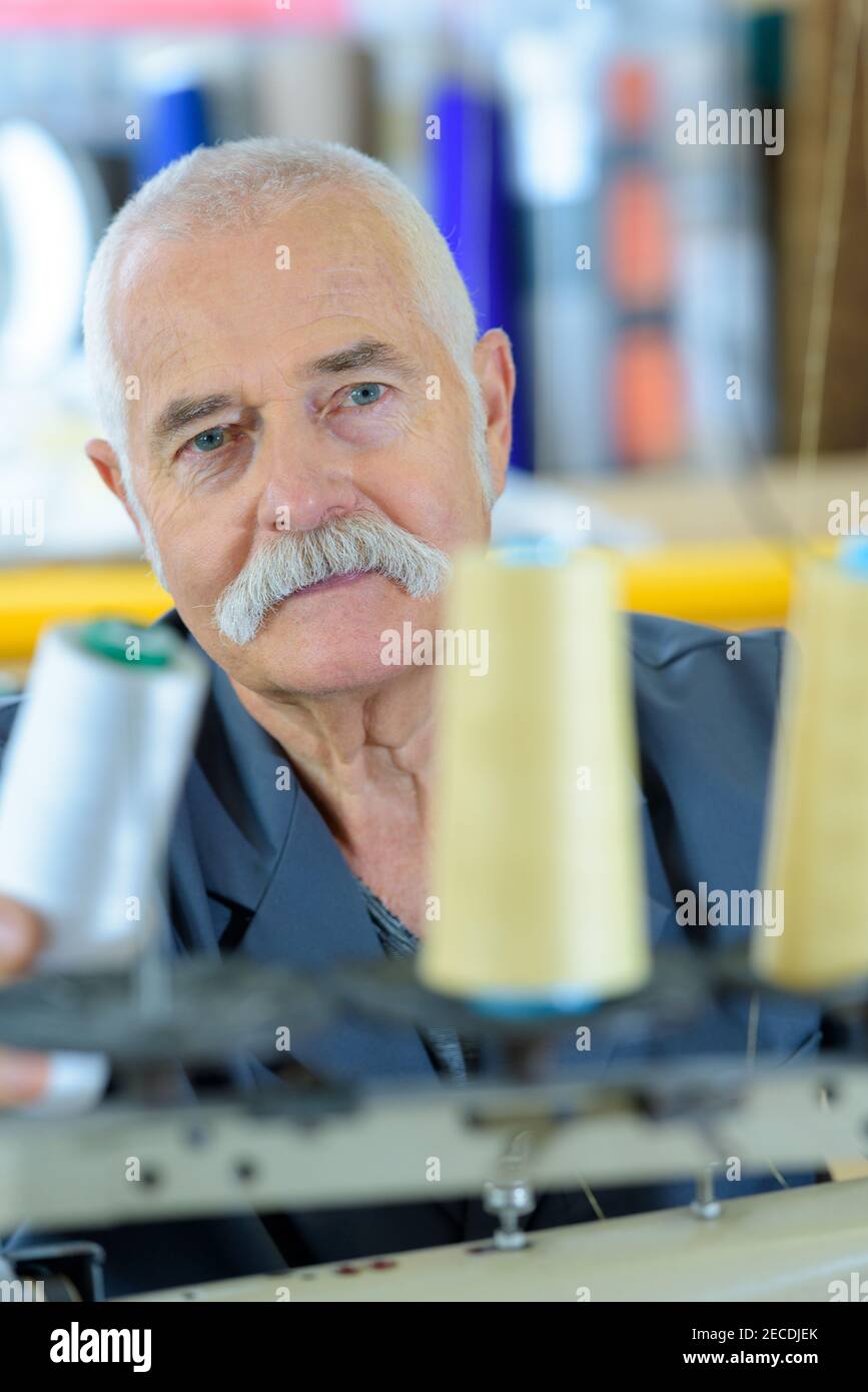 male worker choosing thread for sewing in leather workshop Stock Photo ...