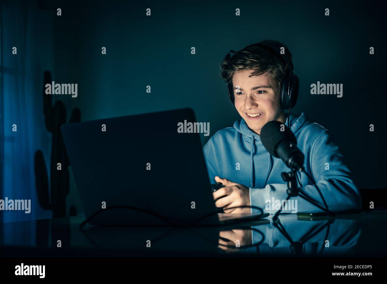 Young blogger and video game streamer playing at home with laptop ...