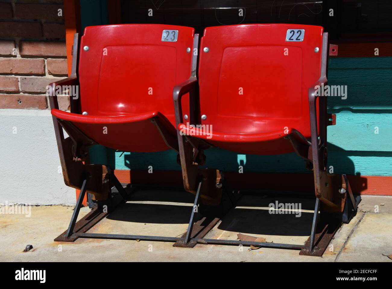 Two red theater seats sit outside in front of a building. Seats have ...
