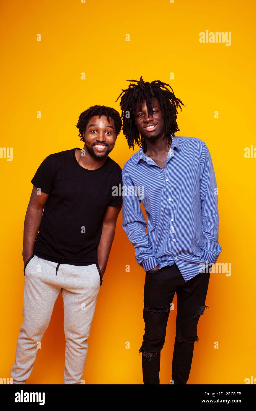 two african american guys posing cheerful together on yellow background ...