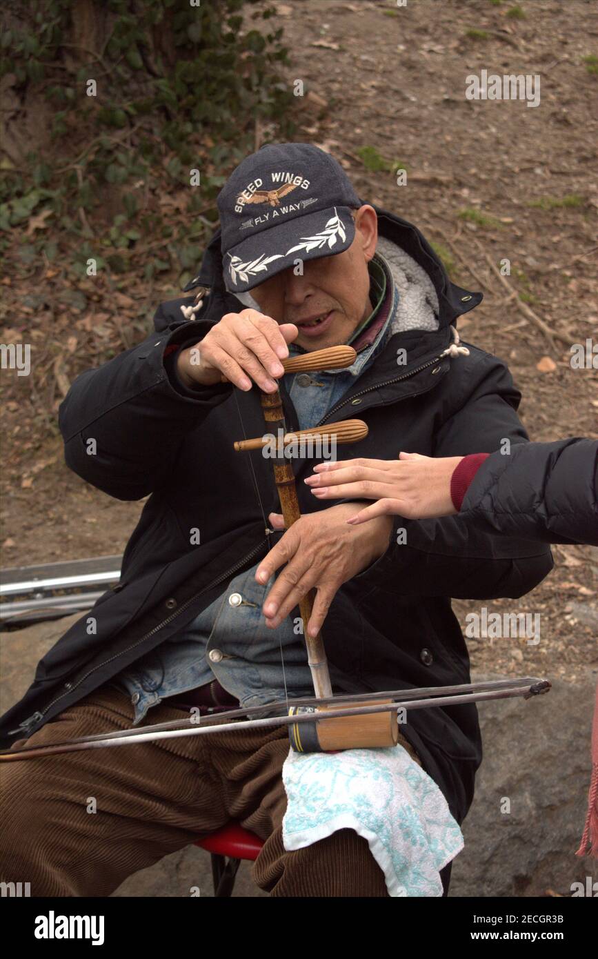 A busking man in Central Park, teaching an audience how to play his ...
