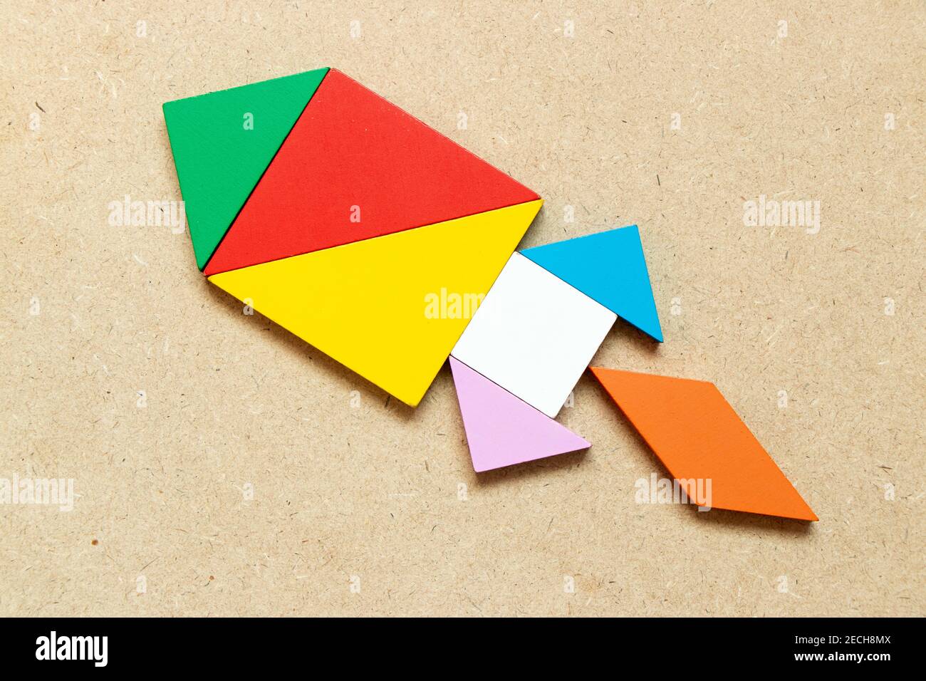 Color tangram puzzle in missile or rocket shape on wood background ...