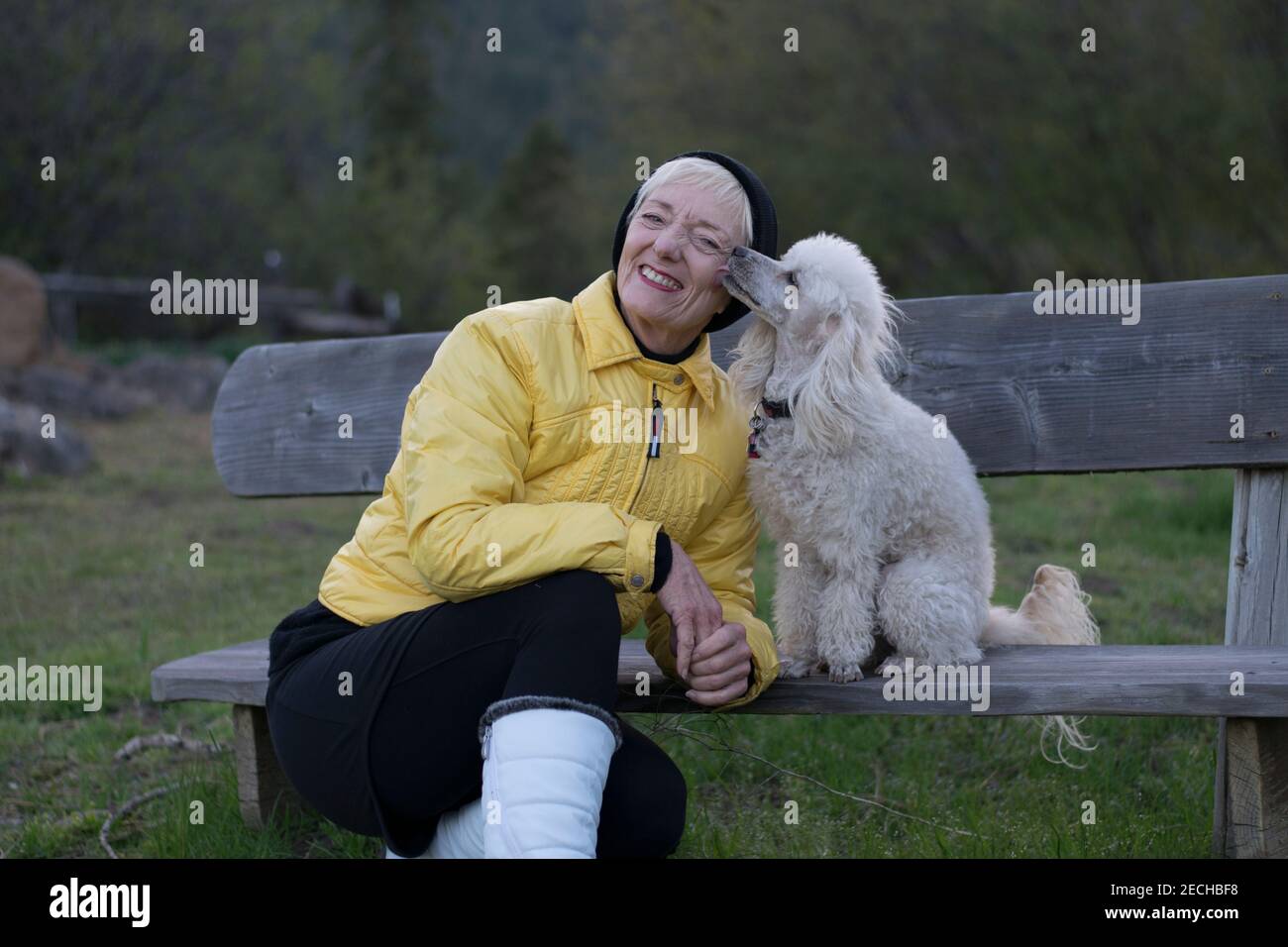 A senior woman and her poodle enjoy the outdoors on a chilly spring day ...