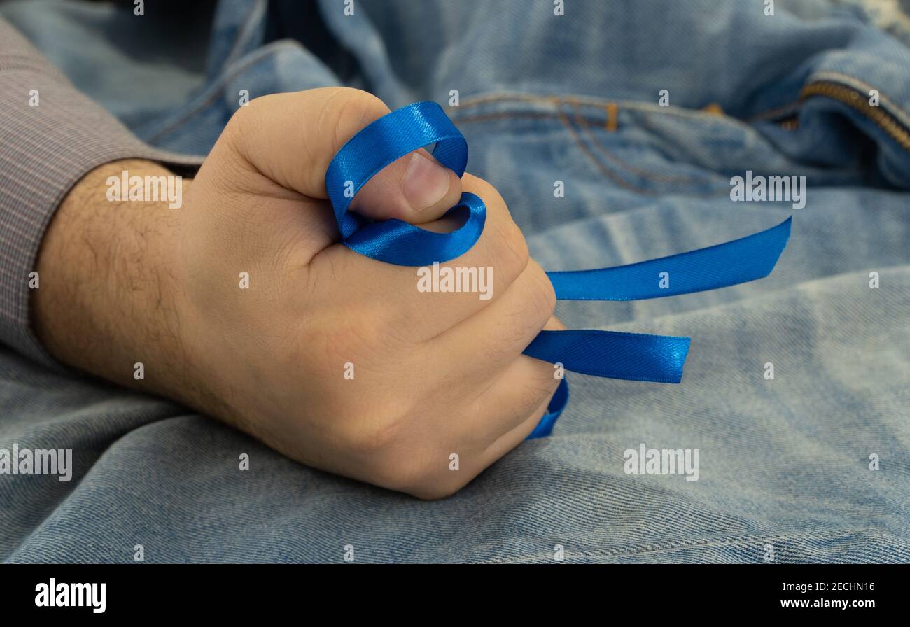blue ribbon is clenched in his fist, the man holds the ribbon in his ...