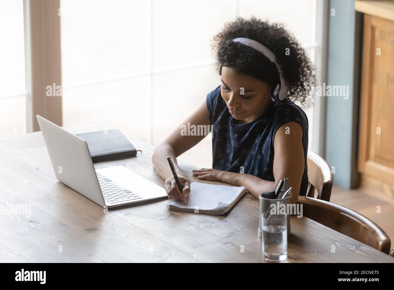 Top view African American woman in headphones taking notes Stock Photo ...