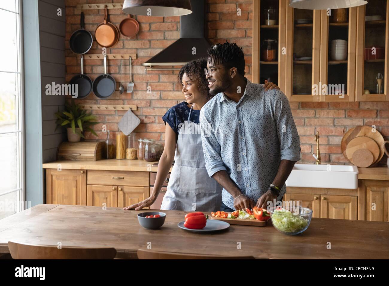 Happy dreamy African American couple cooking in kitchen together Stock ...
