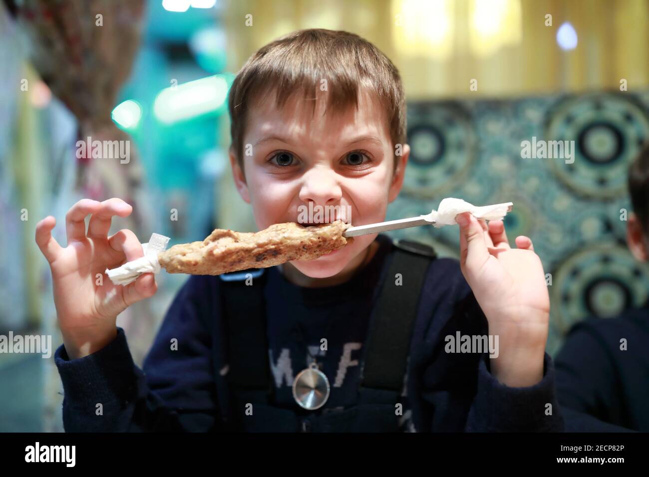 Boy eating kebab on skewer in restaurant Stock Photo - Alamy