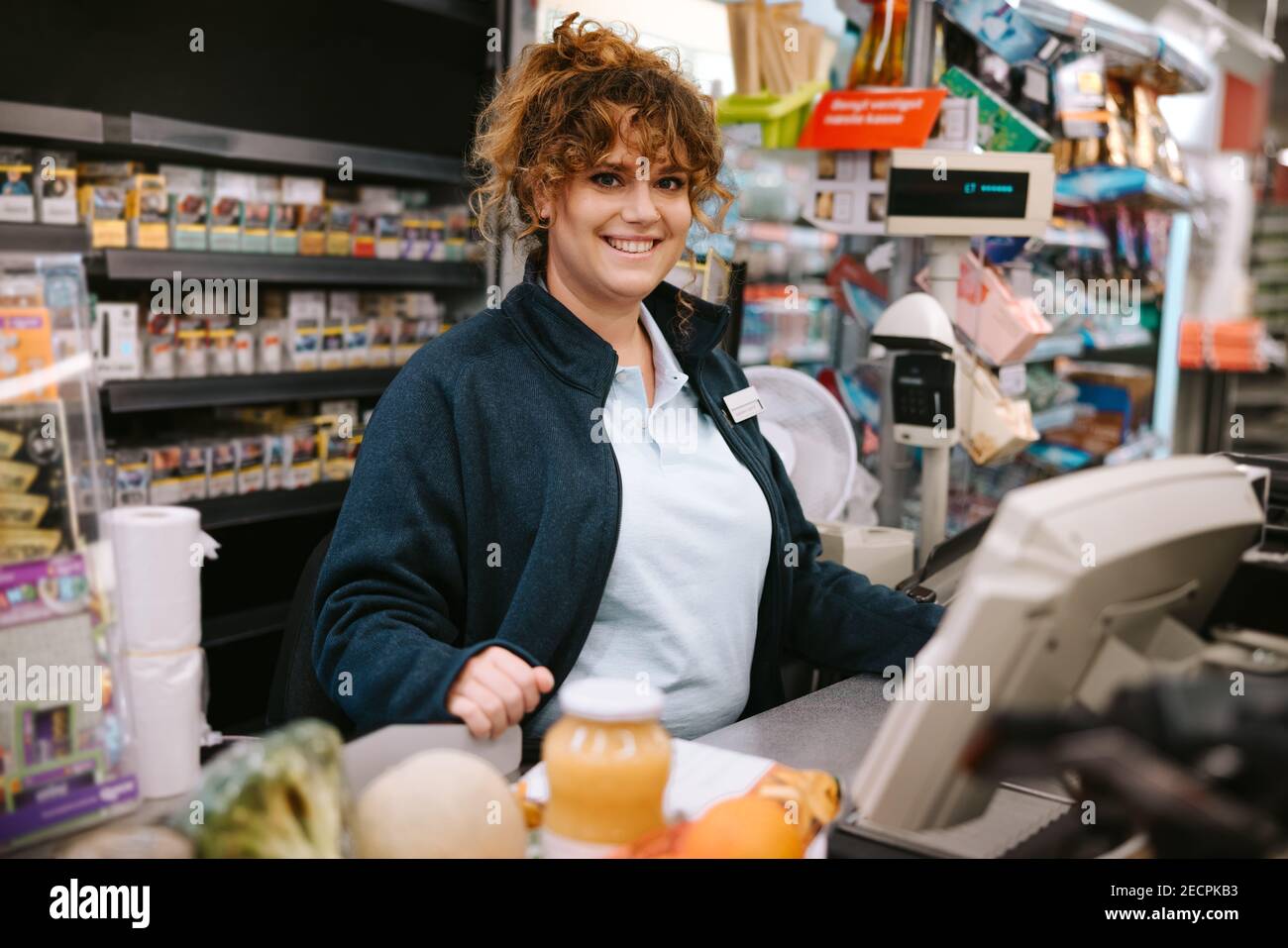 Woman cashier at supermarket. Cash register clerk smiling at camera ...