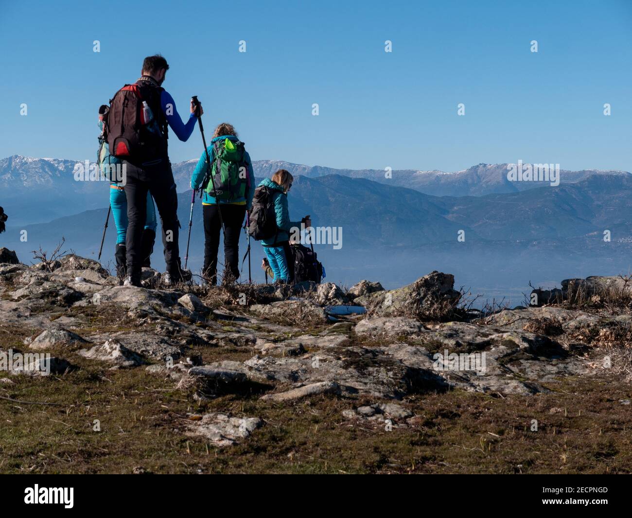 A back view of adventurous hikers hiking down a rocky mountain under ...