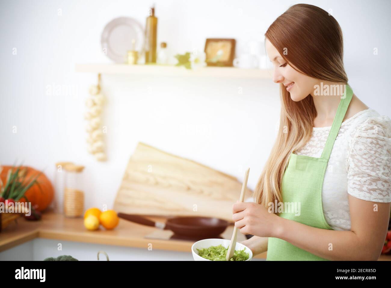 Beautiful woman dressed in apron cooking meal in sunny kitchen Stock ...