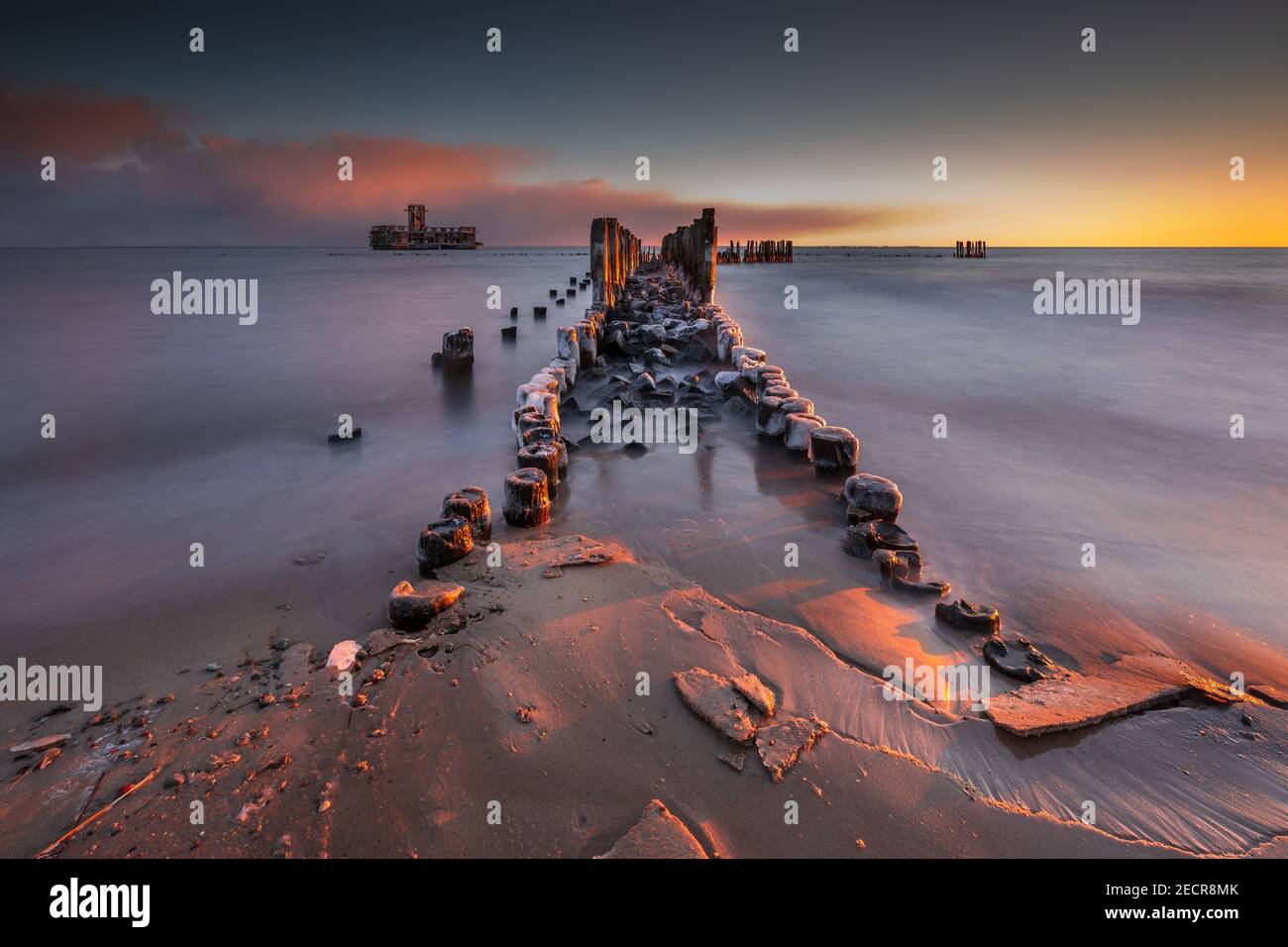 Winter landscape at the sea. Frozen wooden breakwaters line to the ...