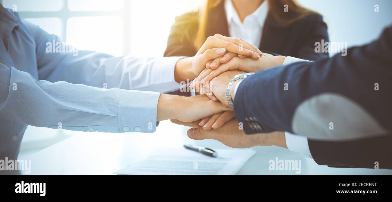 Business team showing unity with their hands together in sunny office ...