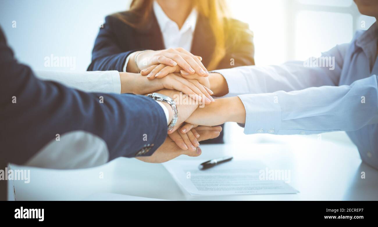 Business team showing unity with their hands together in sunny office ...