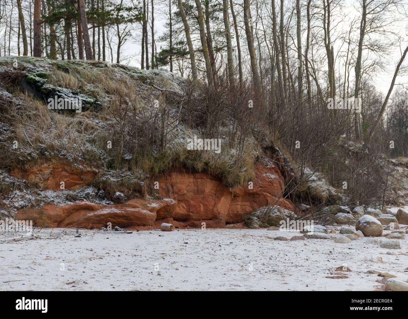 winter landscape with sandy beach, wild sea shore, red sand and clay ...