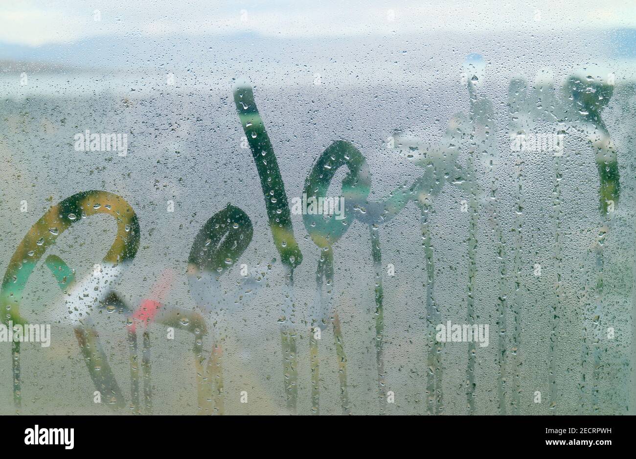 Hand writing inscription of "Relaxing" on the foggy window in a winter ...