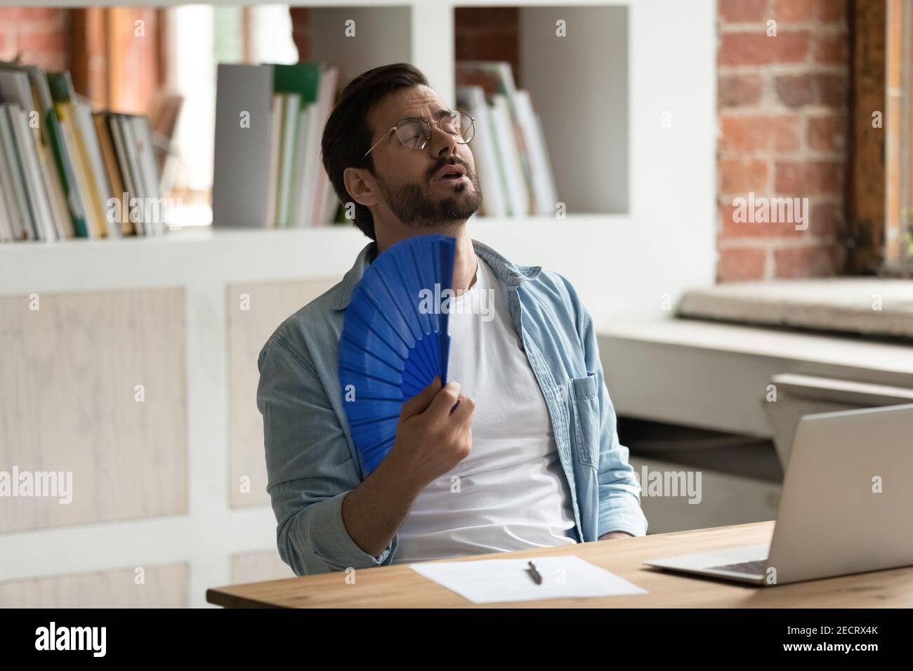 Unwell male employee wave with hand fan Stock Photo - Alamy