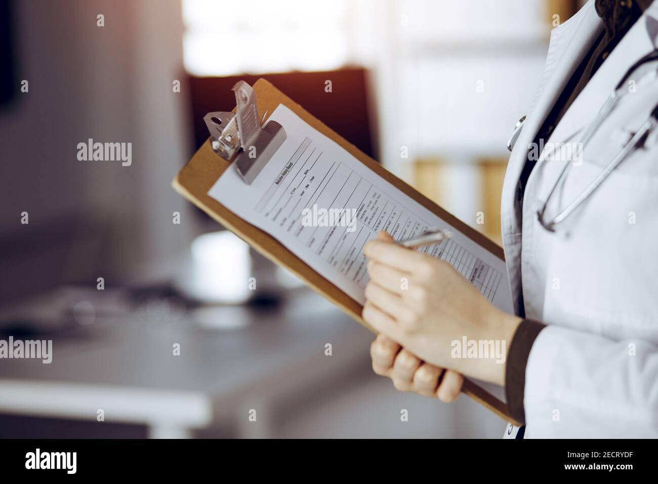 Unknown female doctor using clipboard in sunny clinic. Medicine concept Stock Photo - Alamy