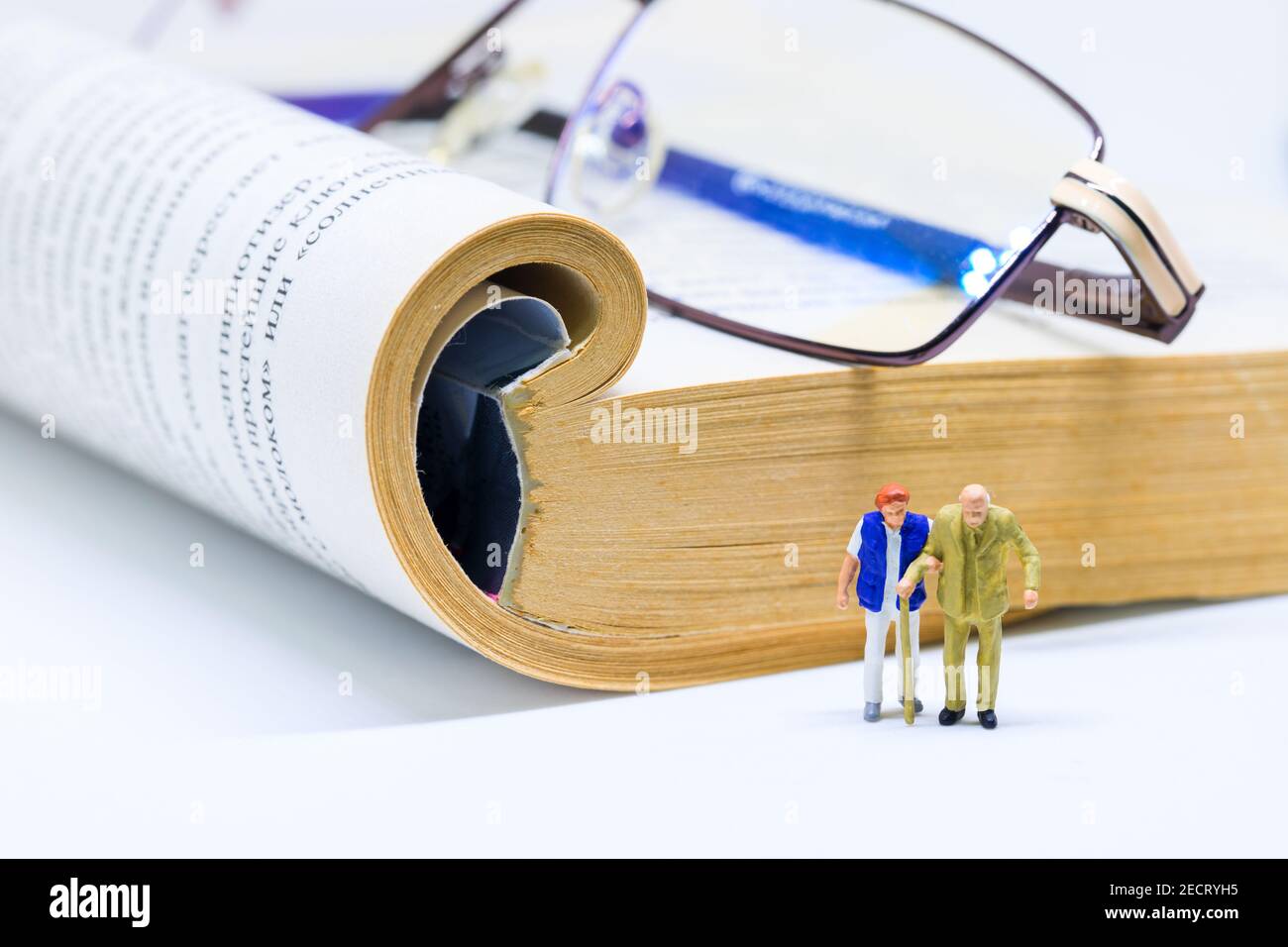 Senior couple miniature figurine with book and glasses on background ...