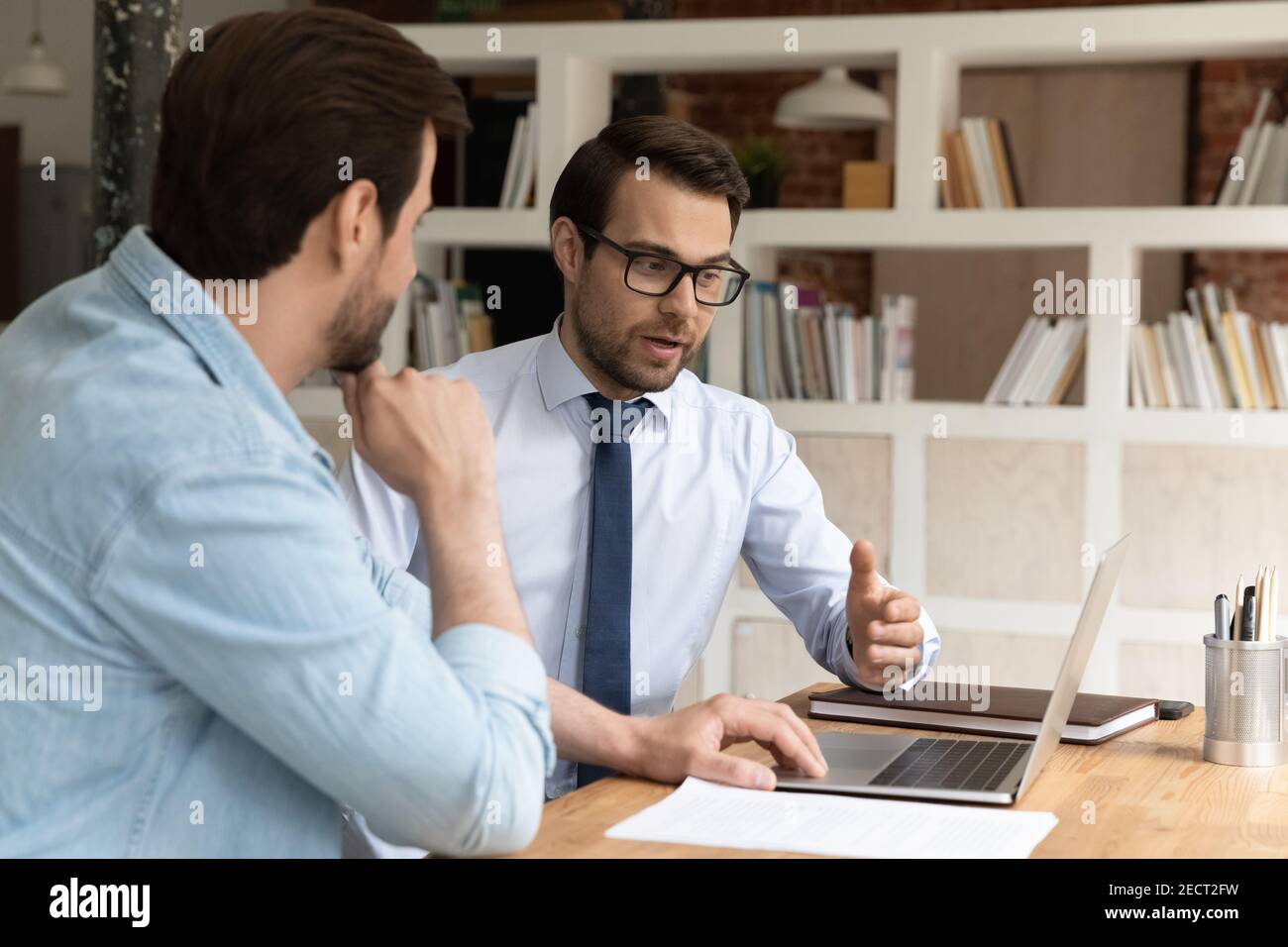 Male colleagues brainstorm working on computer in office Stock Photo ...