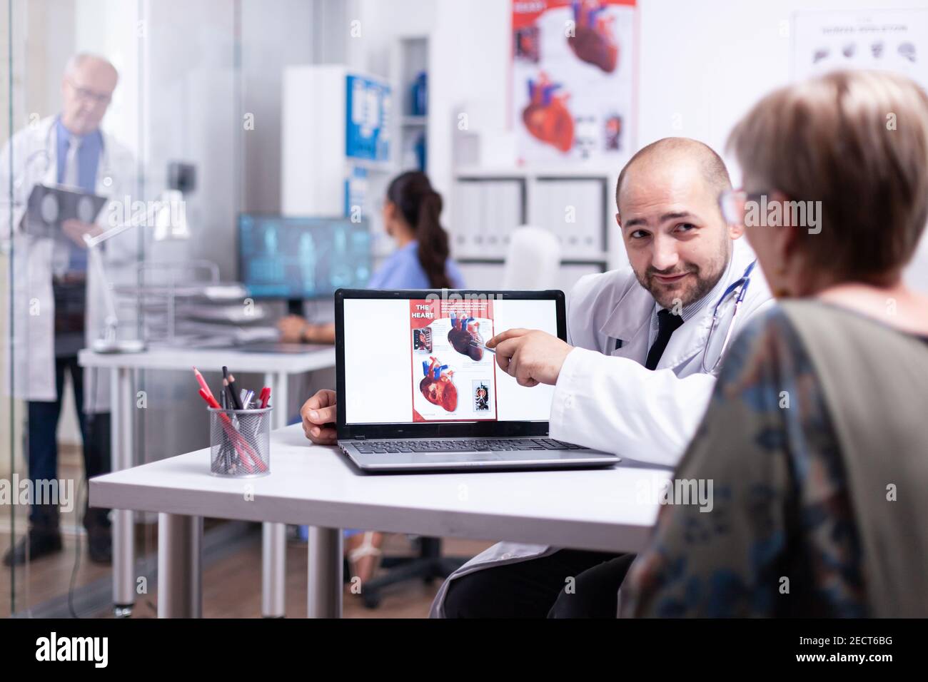 Young doctor explaining heart disease pointing on laptop sitting in ...