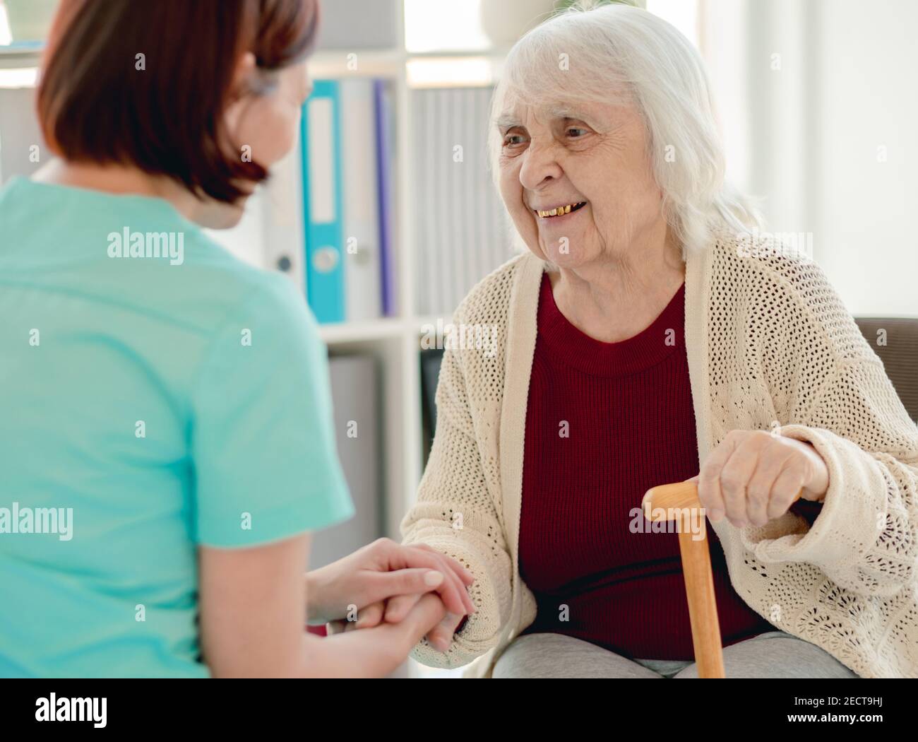 Old lady talking to caregiver holding hands Stock Photo - Alamy