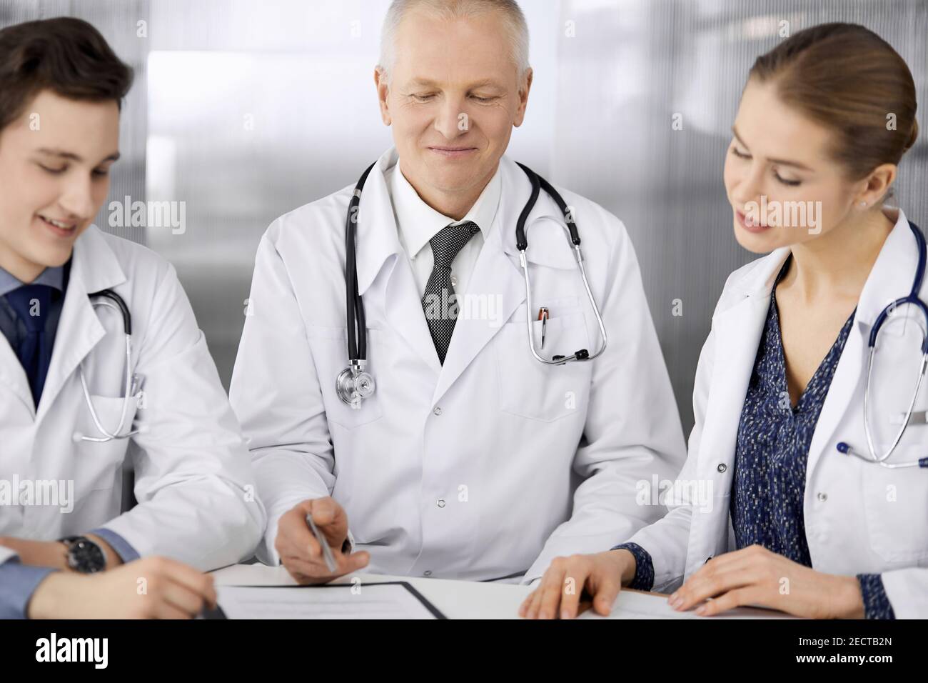 Doctors colleagues and elderly therapist discussing current disease ...