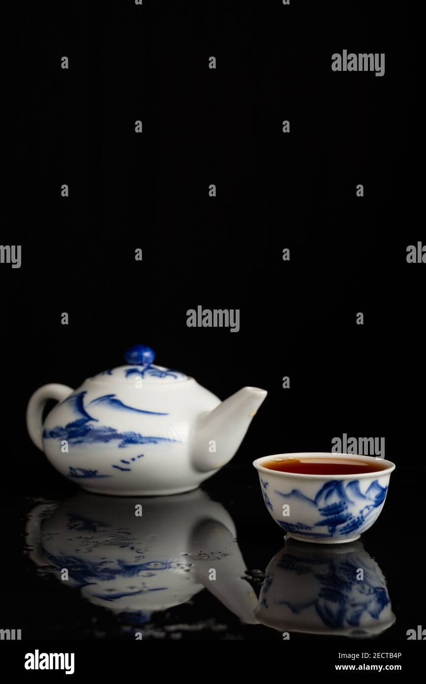 View of blue Chinese teapot and cup, with reflection, on black ...