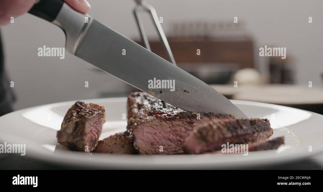man slicing new york steak on white plate, wide photo Stock Photo - Alamy