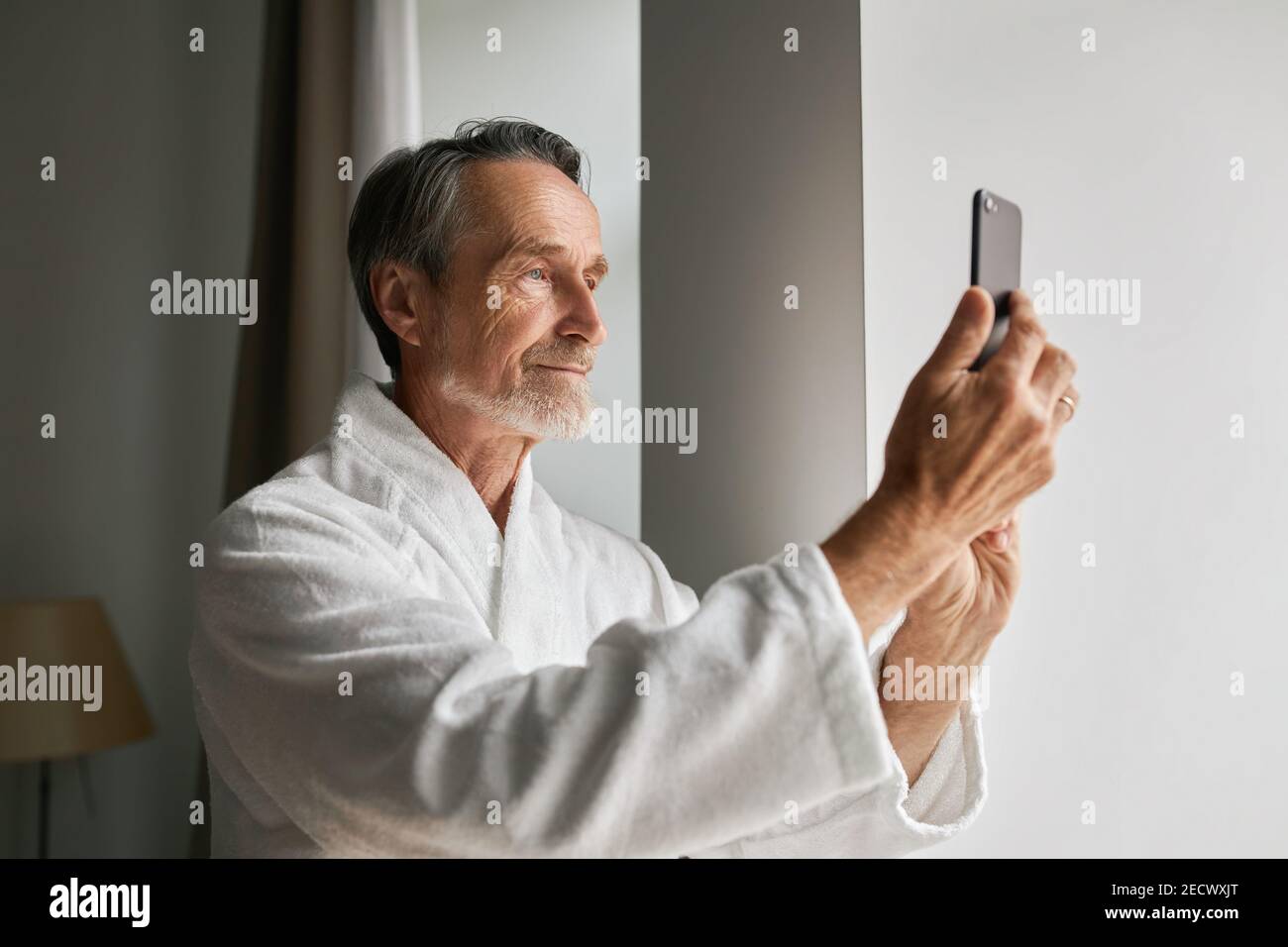 Senior man taking photographs on his smartphone from a hotel room Stock ...