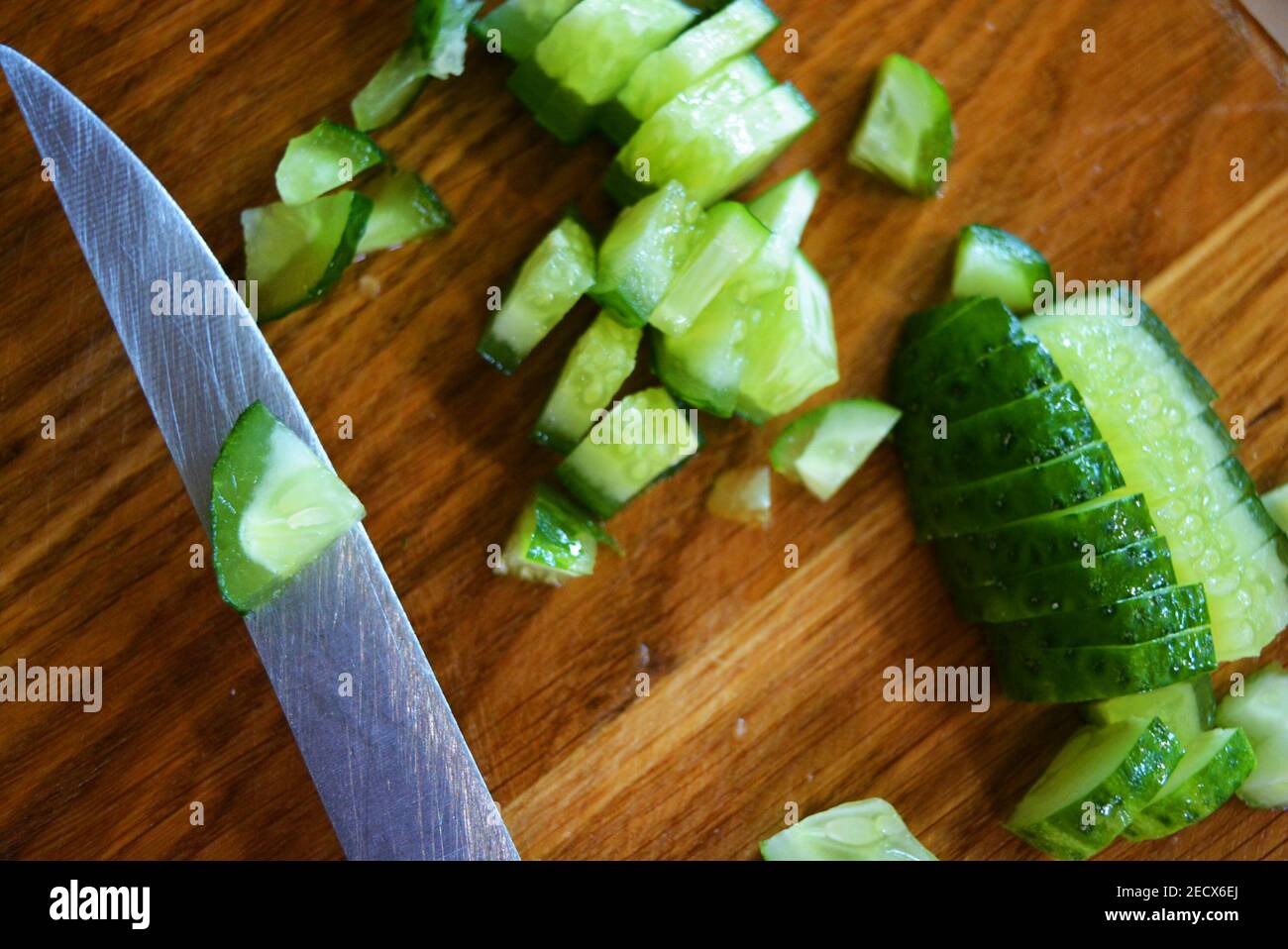 Green fresh sliced cucumbers for a summer salad with a metal kitchen ...