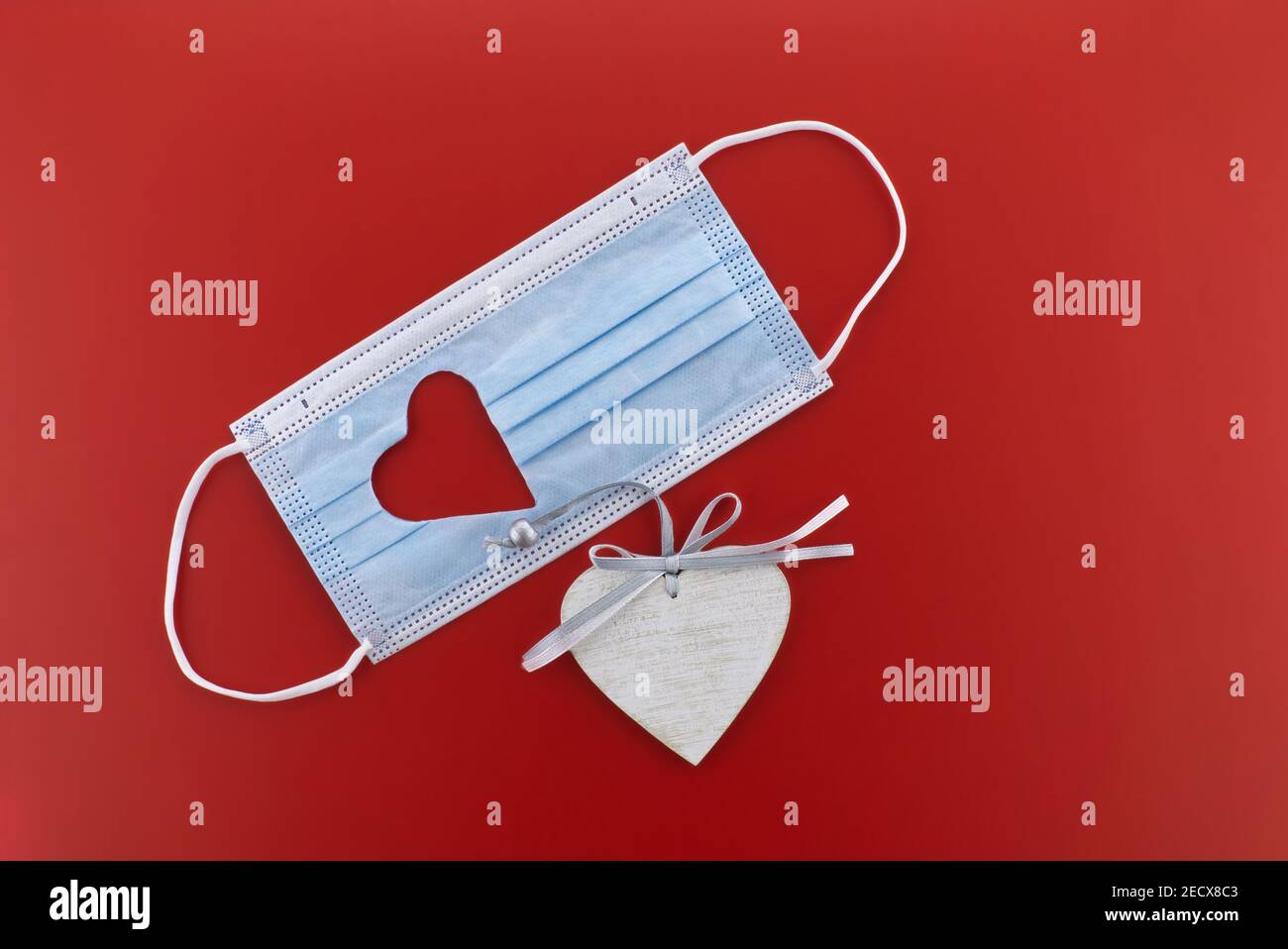 Face mask with a cut-out heart shape over red background with free copy ...