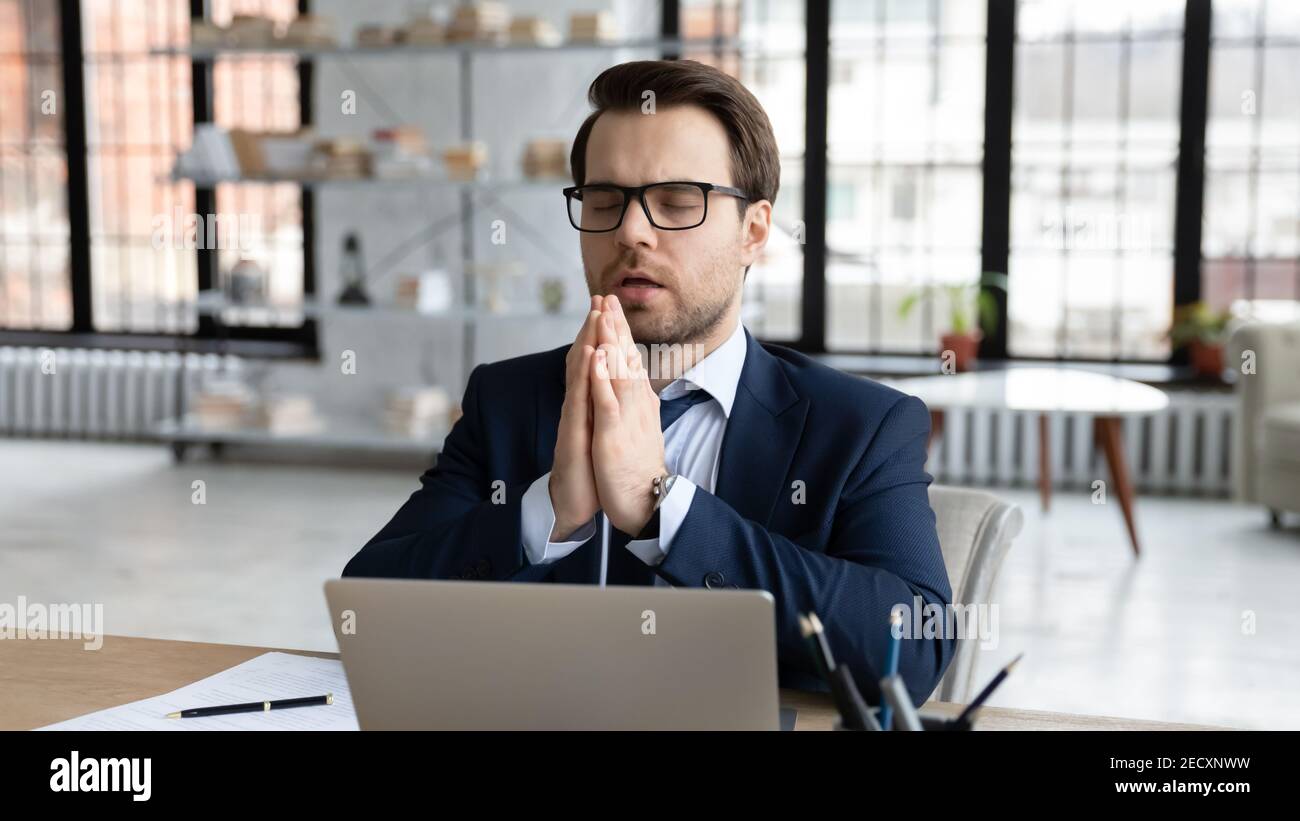 Religious Caucasian businessman pray at workplace in office Stock Photo ...