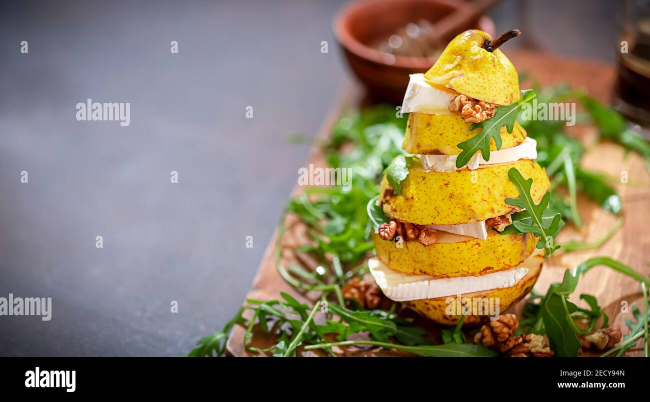 Tower pear with cheese, walnuts, arugula, with honey on a dark wooden ...