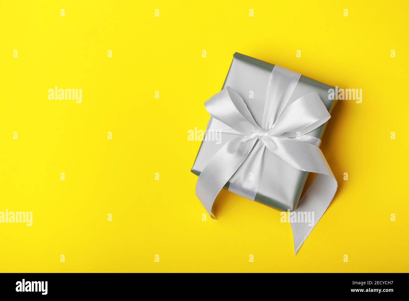 Trendy attractive minimalistic gray gift on the yellow background ...