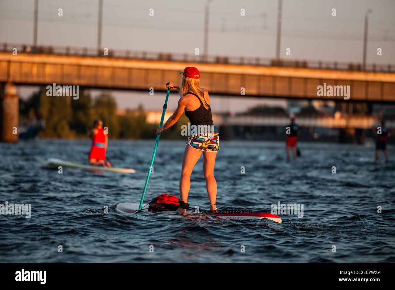 A blonde female on paddleboard along the river Stock Photo - Alamy