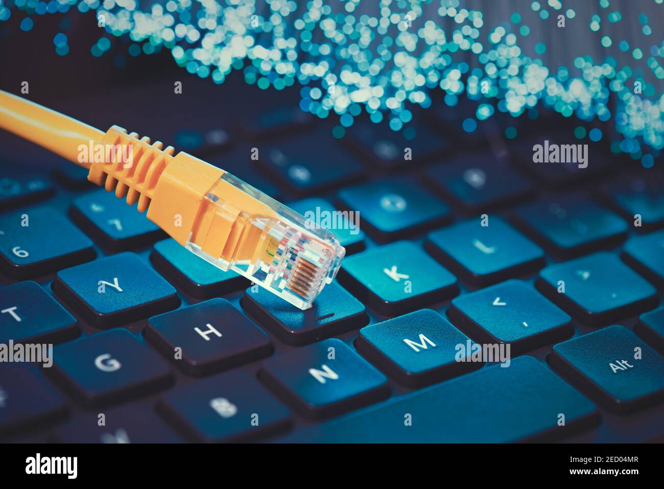 Internet cable, RJ-45 plug on laptop keyboard. High speed fiber optic ...