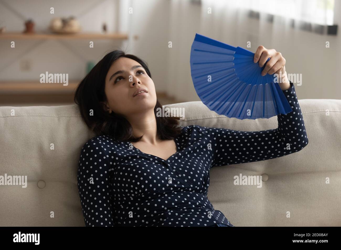 Exhausted young asian woman fanning herself suffering from extreme heat ...
