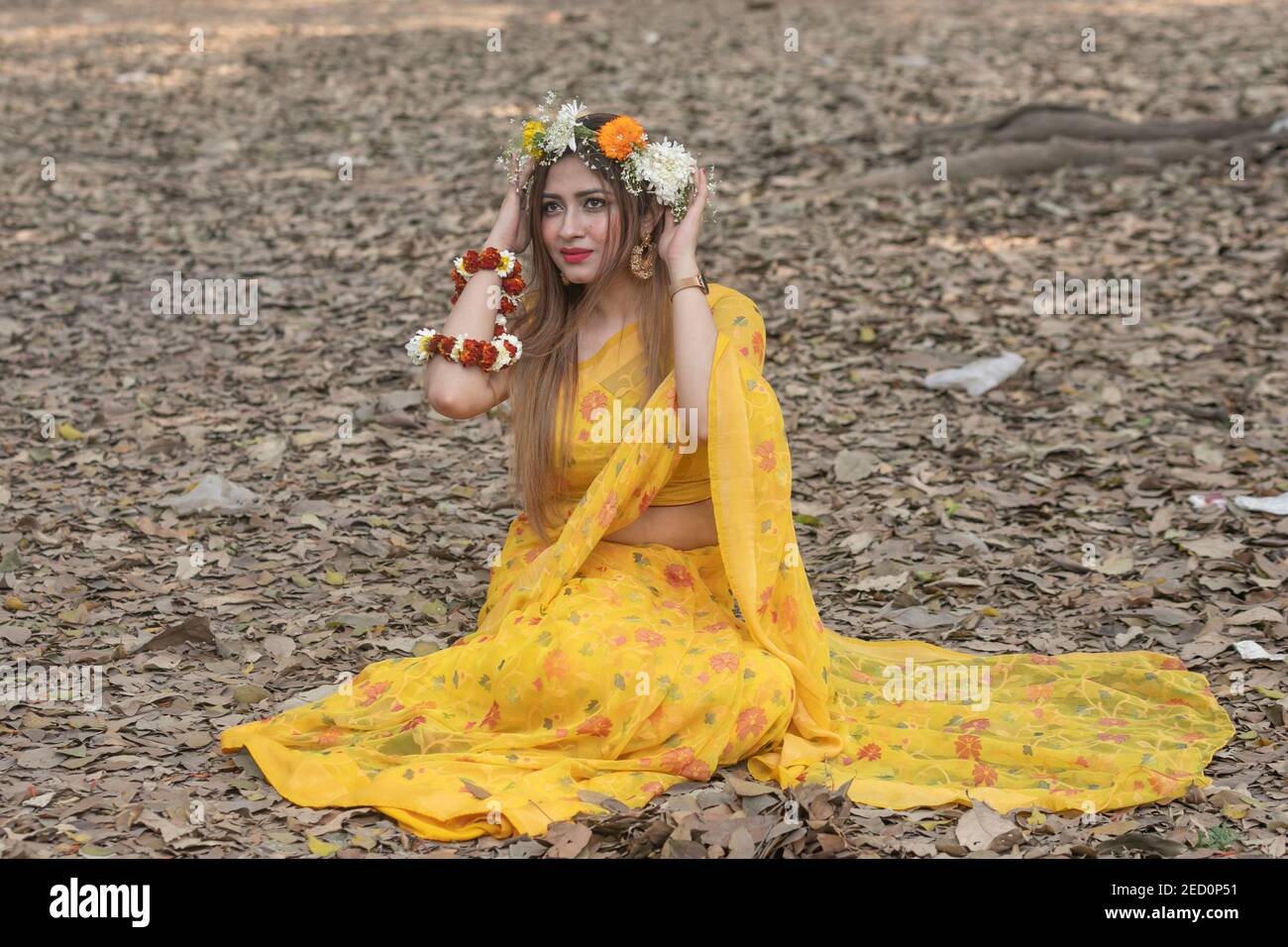 A woman poses for a picture wearing a yellow saris and a flower crown ...