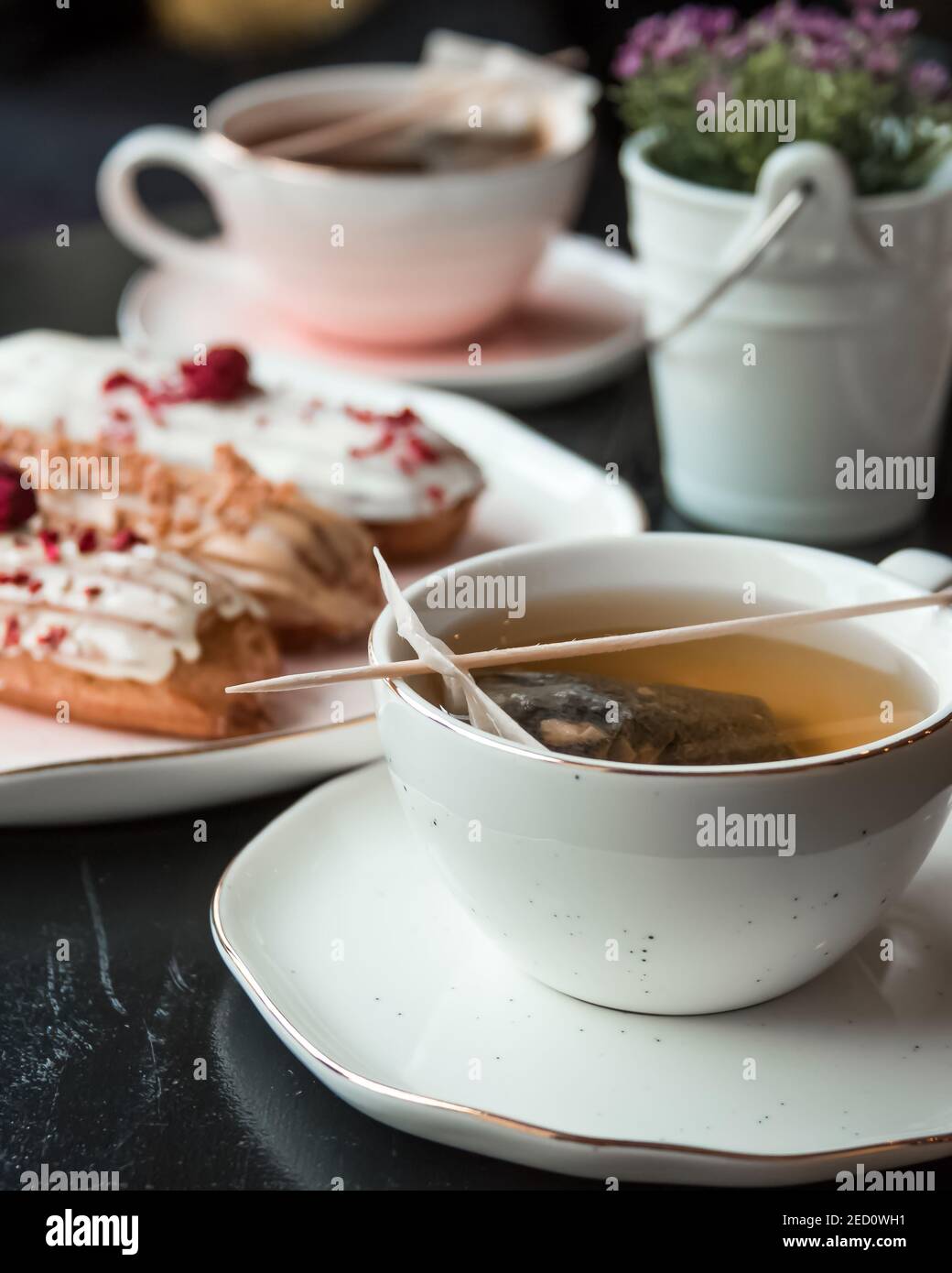 A vertical shot of a cup of tea and French eclairs Stock Photo - Alamy