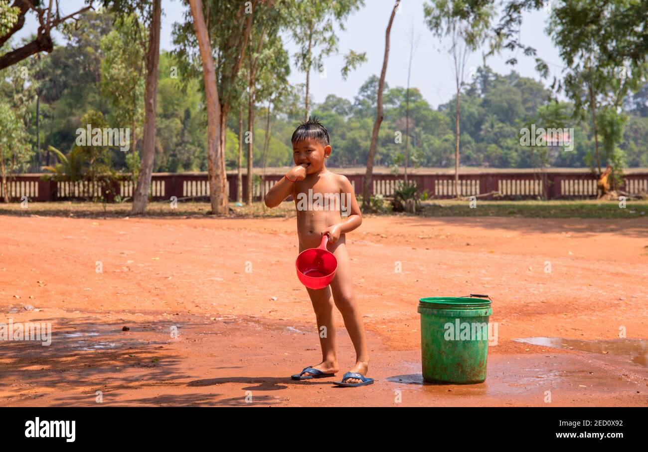 Siem Reap, Cambodia - April 15, 2018: Young boy plays with water on street. Khmer New Year ...