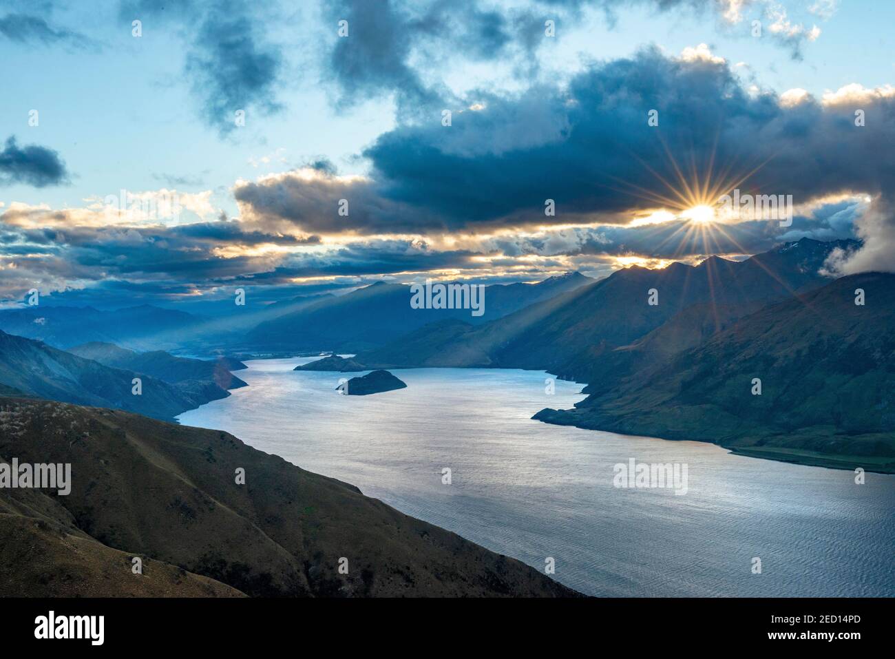 Last rays of sun shining through cloudy sky, view of Lake Wanaka at ...